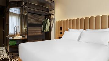 Quarto de hotel com cama, espelho, guarda-roupa e mesa de cabeceira.