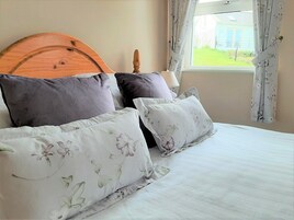 Cama bem arrumada com almofadas estampadas e cabeceira de madeira.