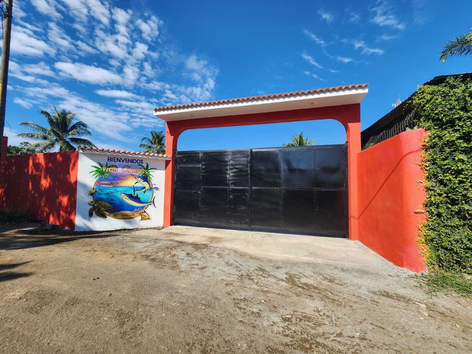Uma entrada com portão e um mural retratando uma cena de praia e uma tartaruga.