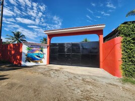 Uma entrada com portão e um mural retratando uma cena de praia e uma tartaruga.