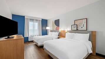 Quarto de hotel com duas camas, televisão e obras de arte nas paredes.