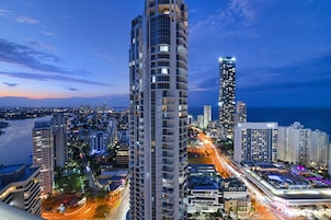 Um hotel de grande porte, com vários andares, localização de destaque na esquina e vista para o horizonte urbano e a costa.