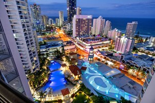 Um hotel moderno com piscina no terraço, várias varandas e vista para o horizonte da cidade e oceano.