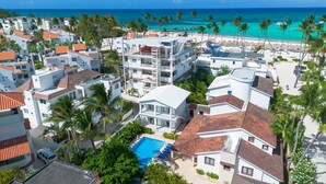 Um resort à beira-mar com edifícios de vários andares, piscina e vista para a praia.
