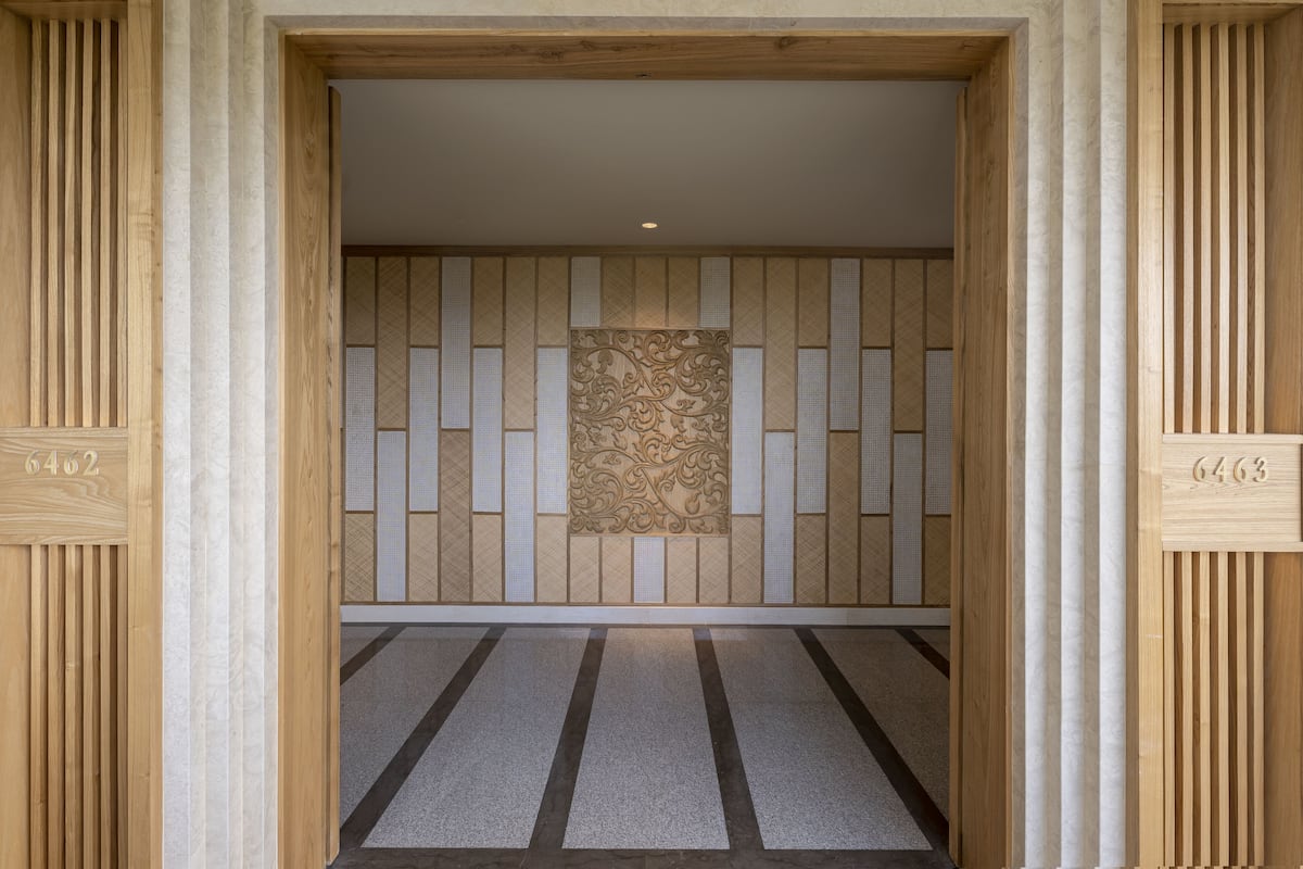 Entrada emoldurada em madeira com painel decorativo e placas numeradas.