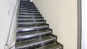 Uma escadaria com degraus de mármore preto e corrimão de metal.