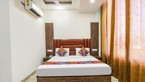 Quarto bem arrumado com cabeceira de madeira, cama com almofadas geométricas coloridas e colcha estampada.
