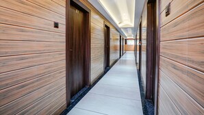 Corredor com painéis de madeira e portas numeradas, dando acesso a quartos individuais.