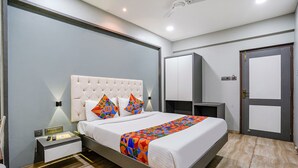 Quarto de hotel moderno com uma cama grande, mesa de cabeceira, guarda-roupa e ventoinha de teto.