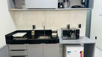 Cozinha compacta com pia, cafeteira, liquidificador e micro-ondas.