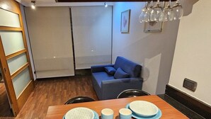 Um espaço de estar compacto com uma mesa de jantar, um sofá e um teto com vigas aparentes.