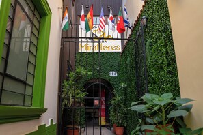 Entrada de hotel com várias bandeiras, uma porta verde e uma placa com a inscrição 'Miraflores'.