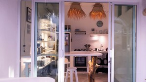 Cozinha moderna com armários brancos, uma ilha central e luminárias pendentes.
