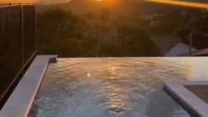 Uma banheira de hidromassagem com vista para o pôr do sol sobre as montanhas.
