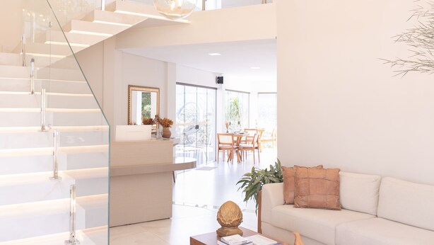 Um interior moderno com escada, área de refeições e sala de estar com sofá e mesa de centro.