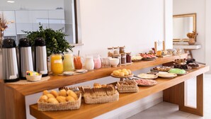 Um buffet de café da manhã com diversas opções de alimentos e bebidas.