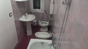 Um banheiro com banheira, duas pias, vaso sanitário e chuveiro.