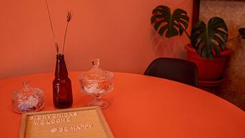 Uma mesa redonda com uma placa de madeira, dois vasos de vidro e um vaso de planta.