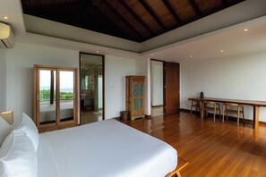 Um quarto espaçoso com uma cama grande, piso de madeira e uma área de jantar com mesa e cadeiras.