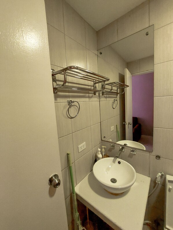 Casa de banho com lavatório branco, espelho e suporte para toalhas.