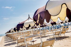 Na praia, areia branca, espreguiçadeiras, guarda-sóis