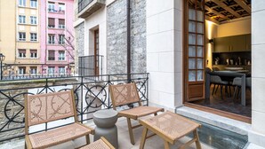Varanda com mobiliário de vime, parede de pedra e vista para edifícios coloridos.