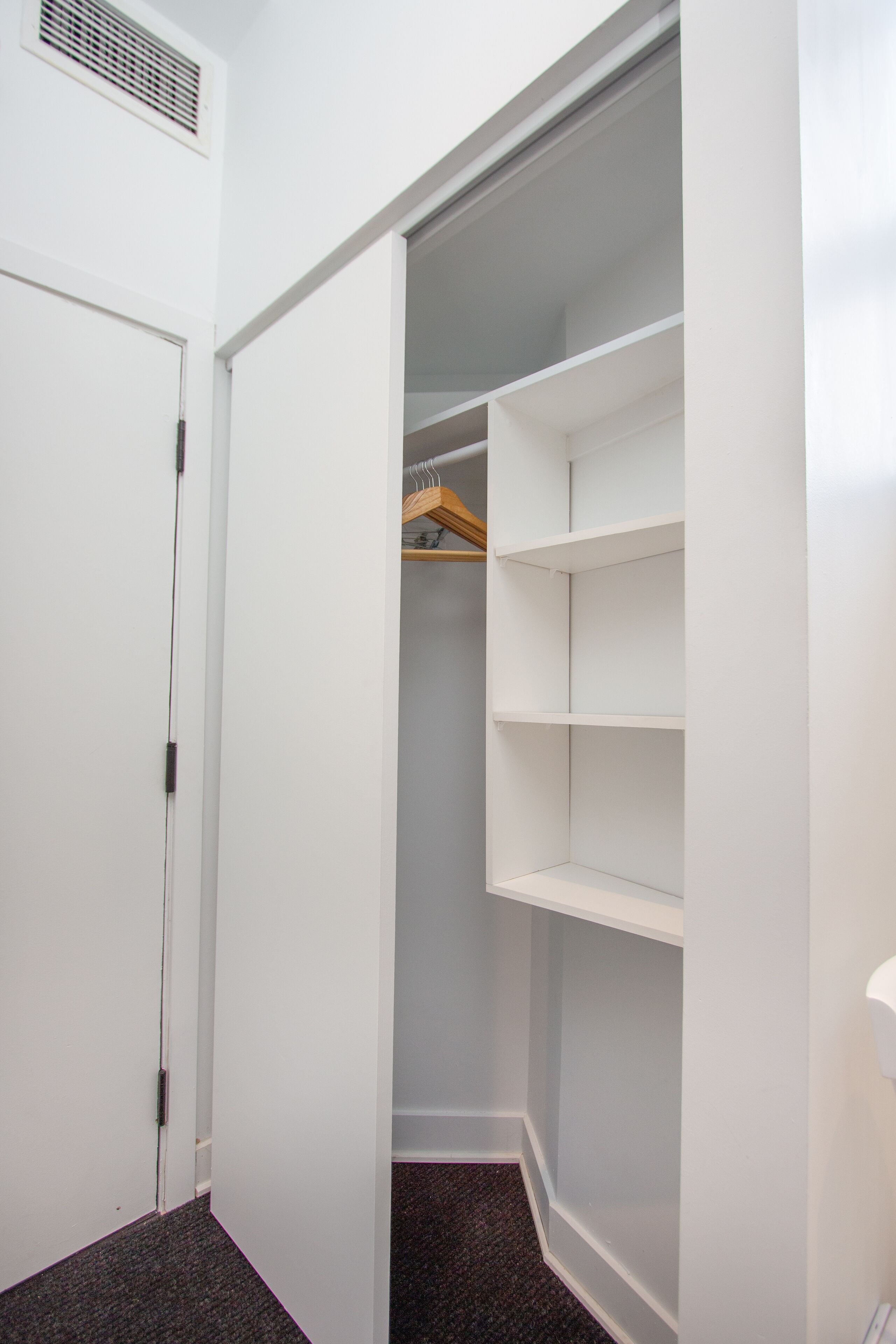 Um closet amplo com portas abertas, mostrando prateleiras e espaço para pendurar roupas.