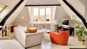 Quarto no sótão com cama beliche, um sofá, uma mesa de centro, uma televisão e uma mesa de jantar.