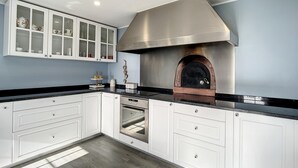 Uma cozinha moderna com armários brancos, uma coifa de aço inoxidável e forno embutido.