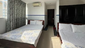 Quarto de hotel com duas camas, uma janela com cortinas, um ar condicionado e um guarda-roupa.