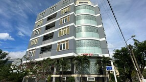 Um hotel de vários andares com design moderno, com varandas e uma entrada destacada.