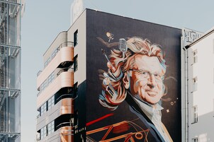 Um mural retrata um homem com cabelos longos em um edifício.
