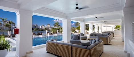 Uma área de estar moderna ao ar livre, com piscina, assentos confortáveis e vista para o horizonte da cidade.