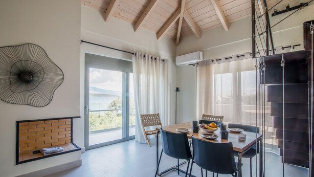 Uma sala de jantar com mesa, cadeiras e vista para o exterior.