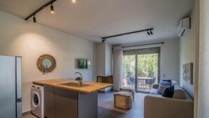 Cozinha moderna com máquina de lavar embutida, bancada de madeira e uma grande janela com vista para um pátio.