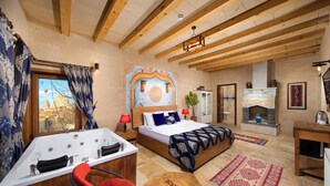 Quarto com cama grande, banheira, teto de madeira e lareira.