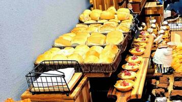 Buffet com diversos alimentos, incluindo pão, waffles e sobremesas.