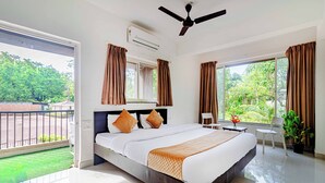 Quarto de hotel com uma cama grande, um ventilador de teto e vista para o exterior.