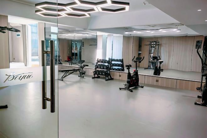 Uma academia moderna com paredes espelhadas, diversos equipamentos de exercício e um espelho grande.