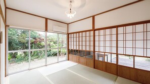 Um quarto japonês tradicional com piso de tatame, portas deslizantes shoji e um ventilador de teto.