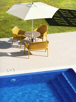 Uma área à beira da piscina com mesa, cadeiras, um guarda-sol e um deck revestido de azulejos.