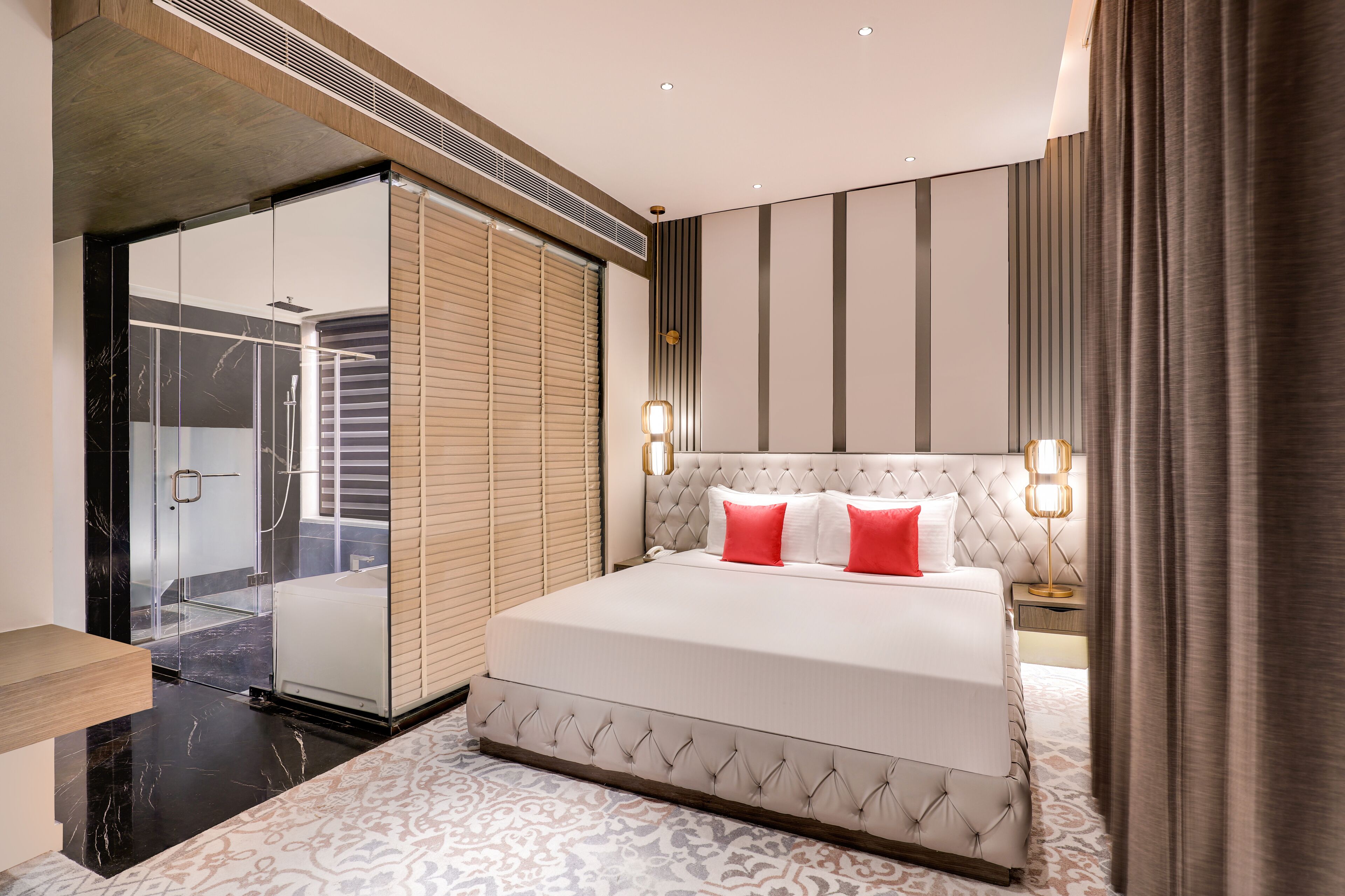 Quarto moderno com uma cama grande, chuveiro de vidro e mesa de cabeceira com abajur.
