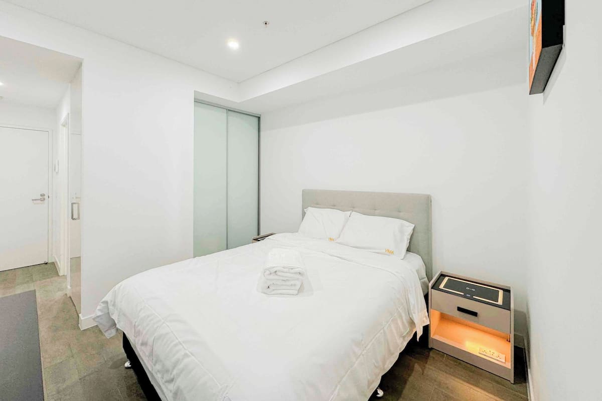 Quarto moderno com cama, mesa de cabeceira e guarda-roupa.