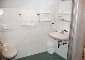 Casa de banho com sanita, lavatório e zona de duche.