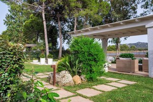Uma área de pátio com móveis de exterior, uma pérgula e diversas plantas.