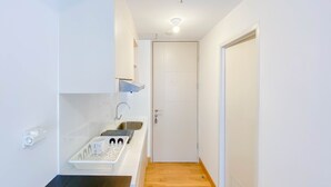 Uma cozinha compacta com pia, bancada e uma porta que dá para outro quarto.