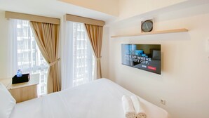 Quarto de hotel com cama, televisão na parede, relógio e janela com cortinas.