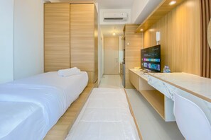 Quarto de hotel com duas camas, uma escrivaninha com computador e televisão.