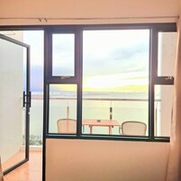 Uma varanda com mesa e cadeiras, com vista para um corpo de água e terra distante.