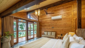 Um quarto amplo com piso de madeira, uma cama, um banco e um ventilador de teto.